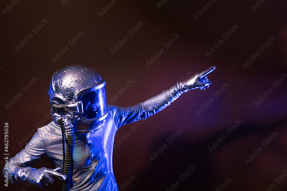 Spaceman in space suit pointing while standing against colored ...