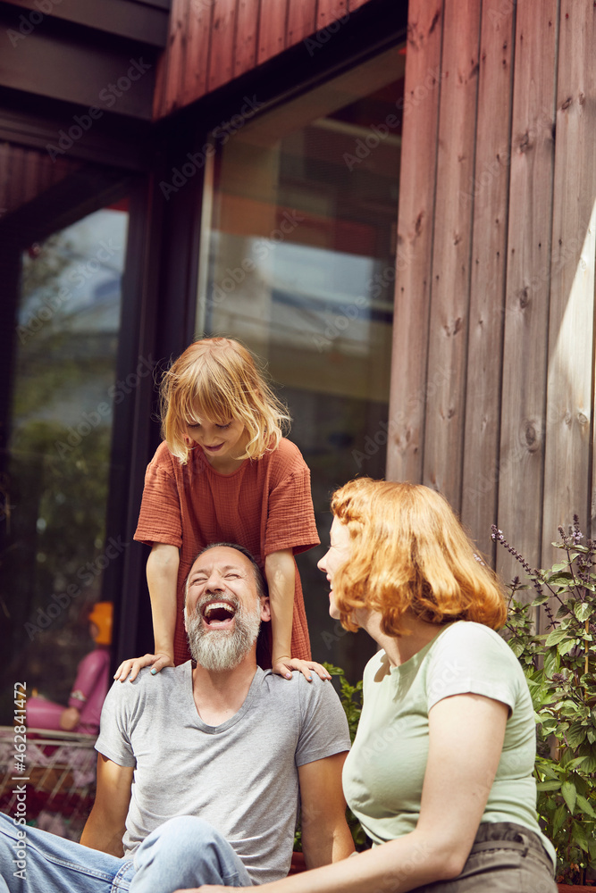 Girl looking at cheerful parents laughing while standing outside tiny ...