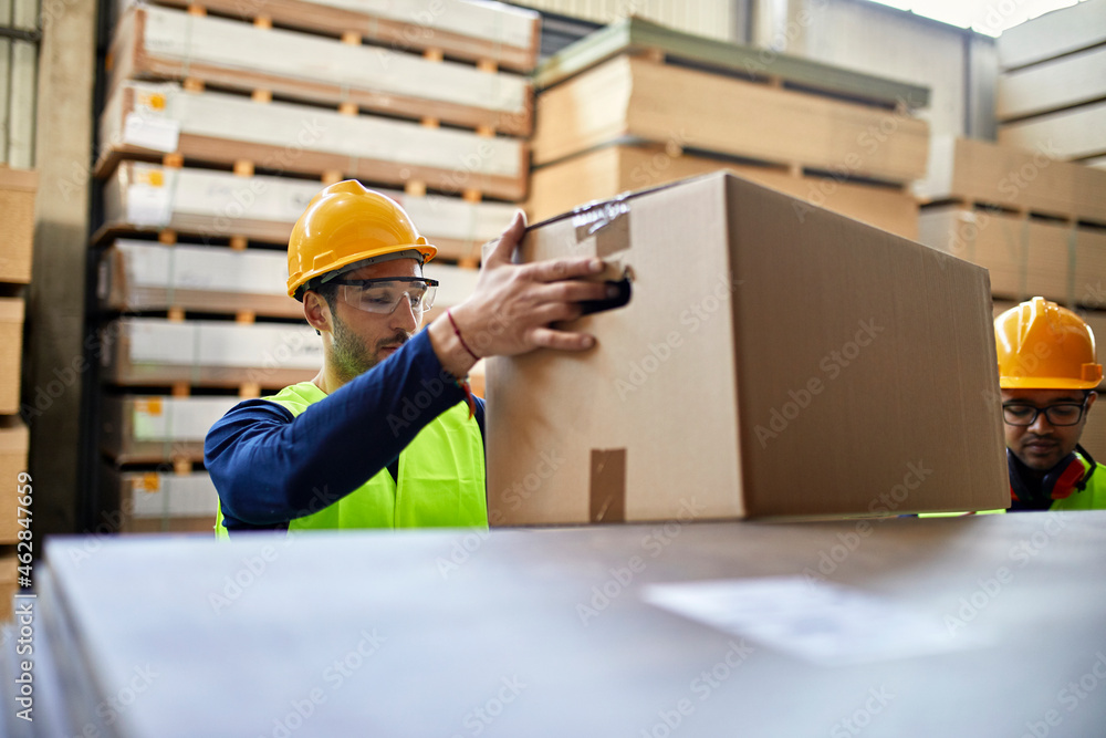 Worker carrying box in factory warehouse Stock Photo | Adobe Stock