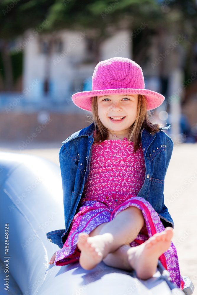 Portrait of fashionable little girl sitting on rubber raft on the beach ...