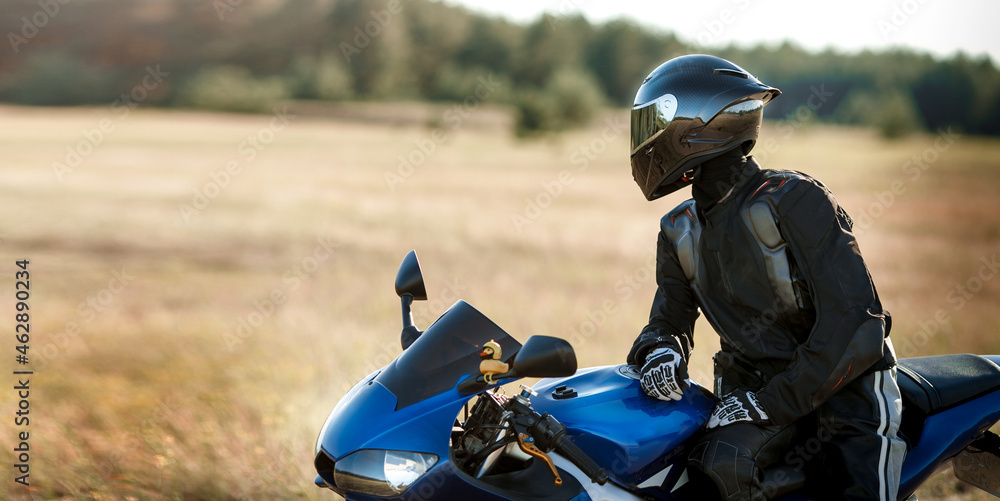 Biker man on a motorcycle in a leather jacket and helmet looks at the ...
