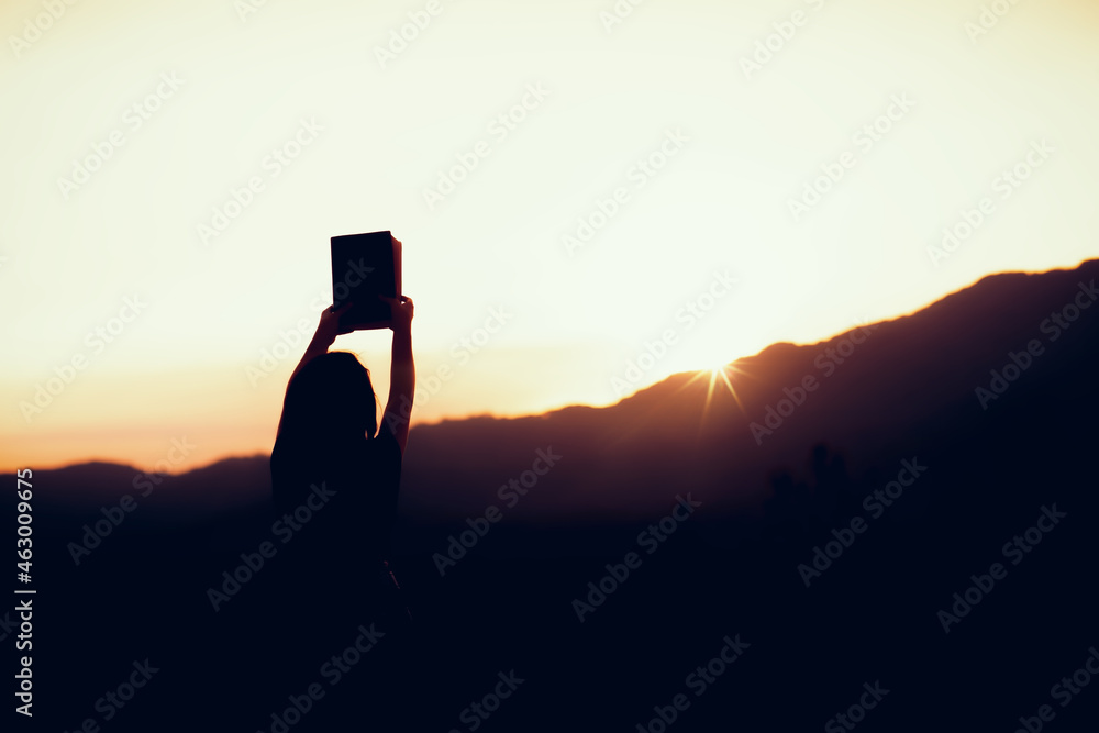 Girl lift Bible up to sky with light sunset background, christian ...