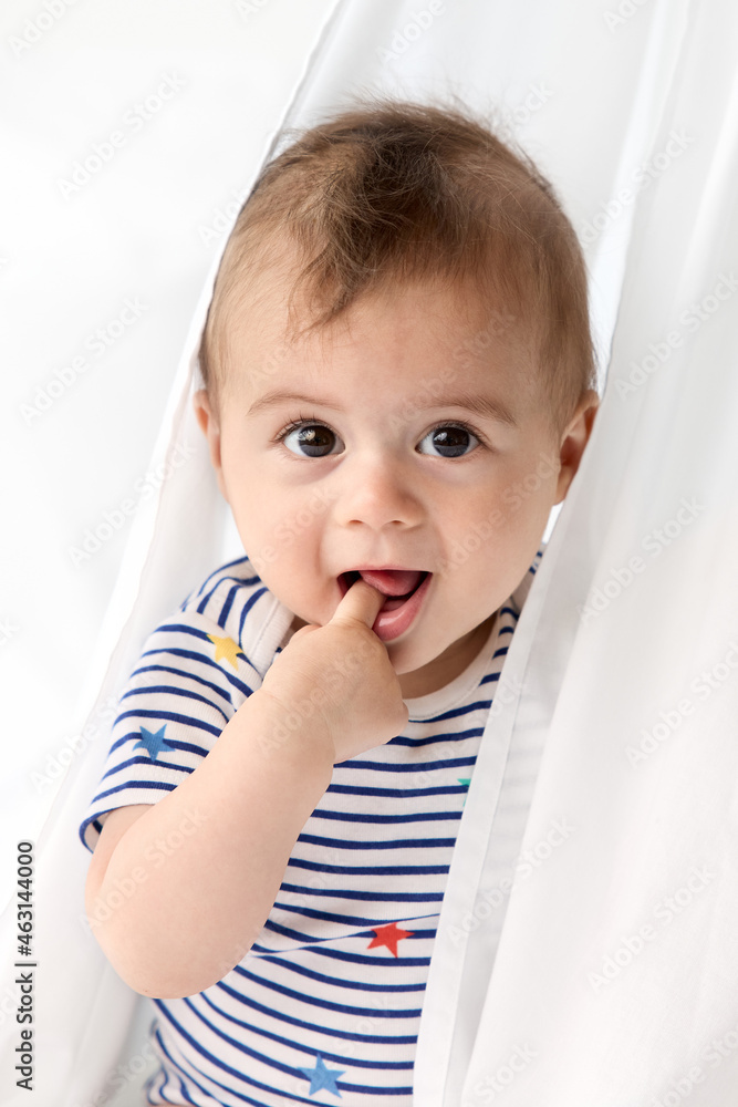 Cute baby face peeking behind white sheet with finger in mouth Stock ...