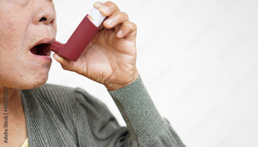 Female senior patient uses brown asthma inhaler for relief asthma ...