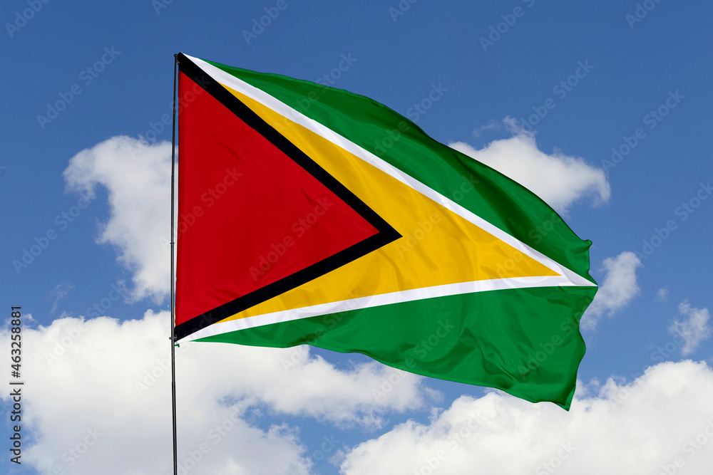 Guyana flag isolated on the blue sky background. close up waving flag of Guyana. flag symbols of ...