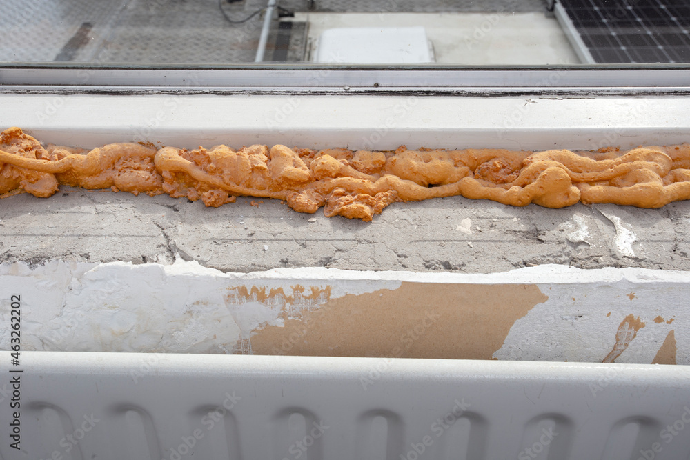 Worker using a polyurethane foam for installation of window sill ...