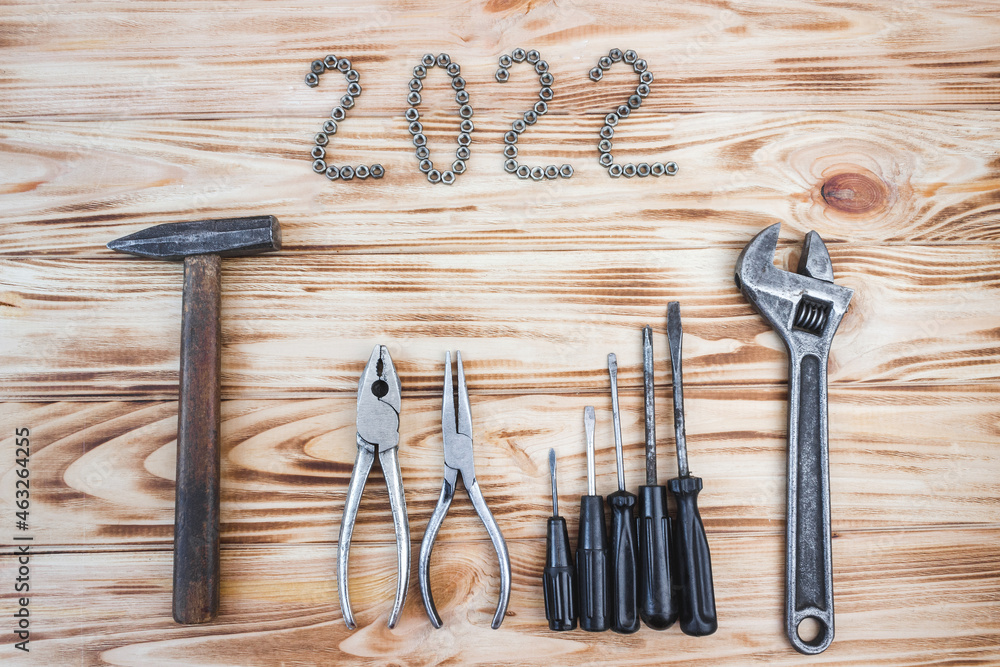 Carpentry tools on a light wood table with 2022 lined with screw nuts ...