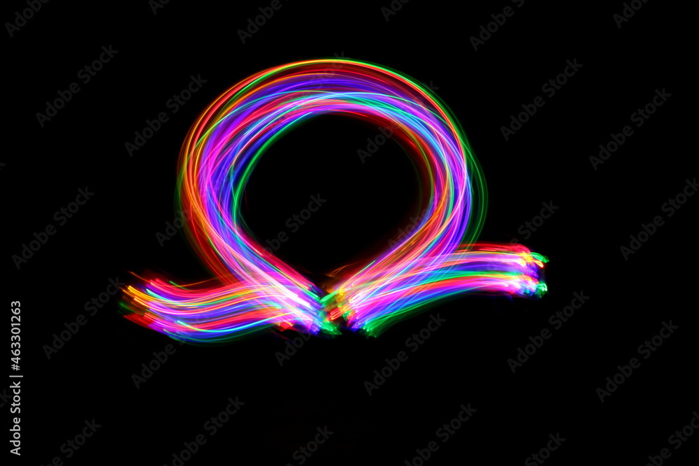 Long exposure photograph of an omega symbol in neon colour in an ...