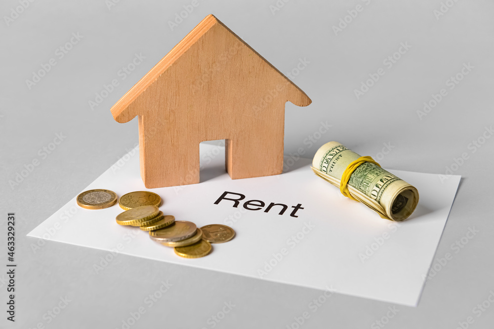 Wooden house with word RENT and money on light background Stock Photo ...