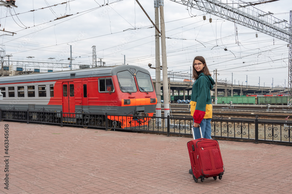 Caucasian girl student in bright clothes with a suitcase going to the ...