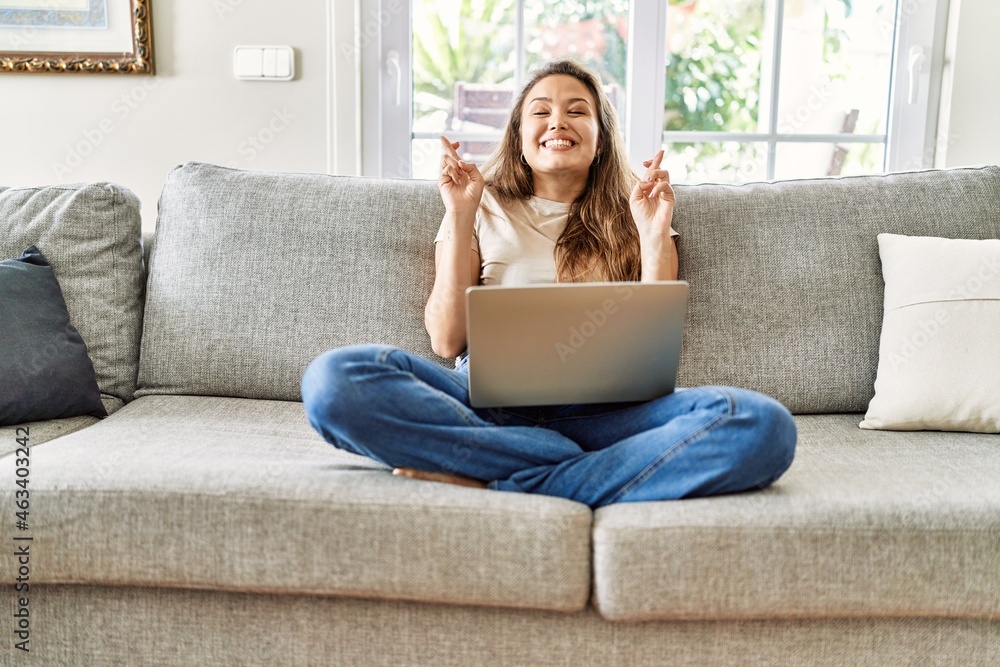 Beautiful young brunette woman sitting on the sofa using computer ...