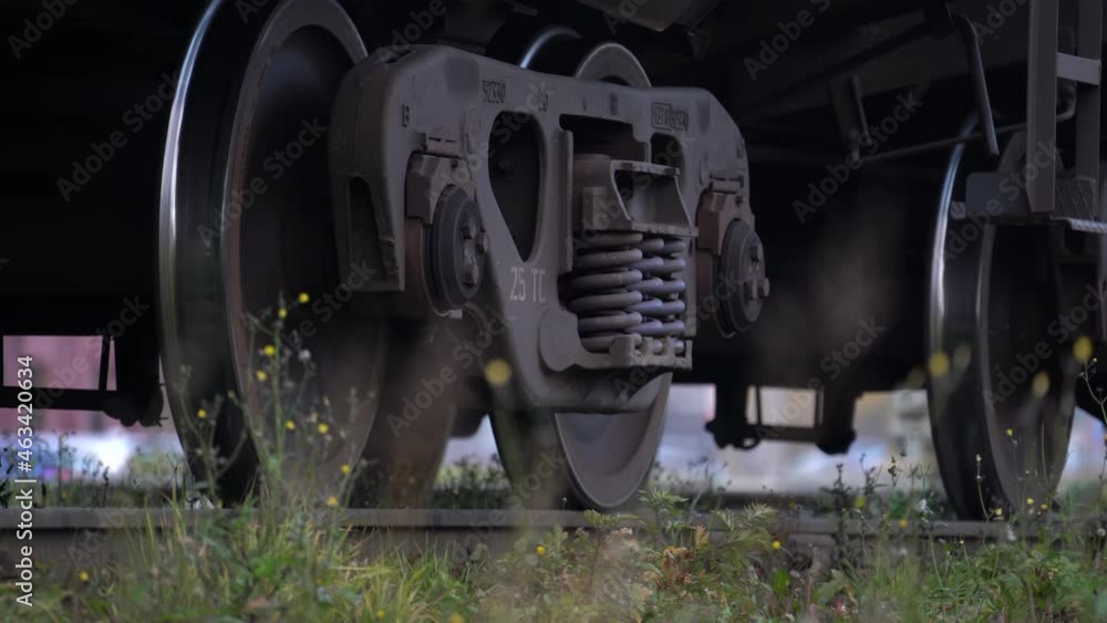 Cargo train rides on railroad moving slowly by rail at the station. Closeup of wheels on railway ...