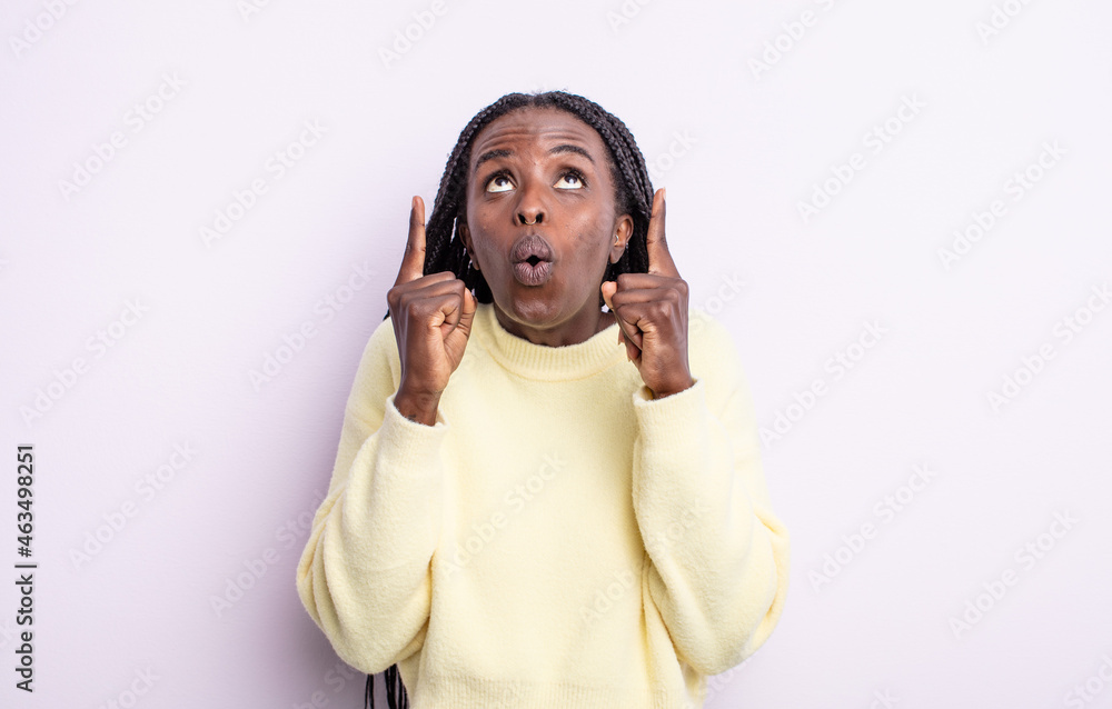 black pretty woman feeling awed and open mouthed pointing upwards with ...