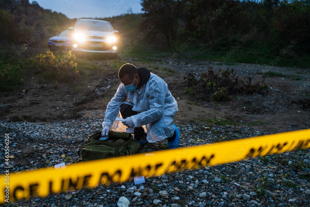 Forensic police investigator collecting evidence at the crime scene in ...