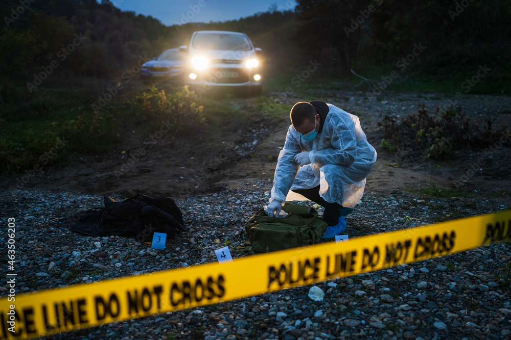 Forensic police investigator collecting evidence at the crime scene in ...