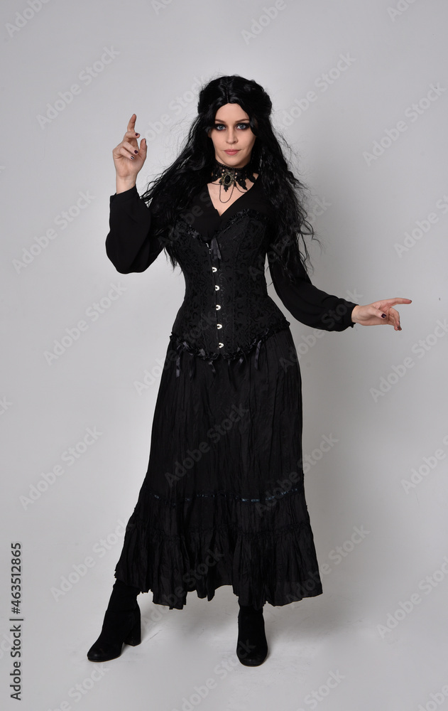 Full length portrait of dark haired woman wearing black victorian witch ...