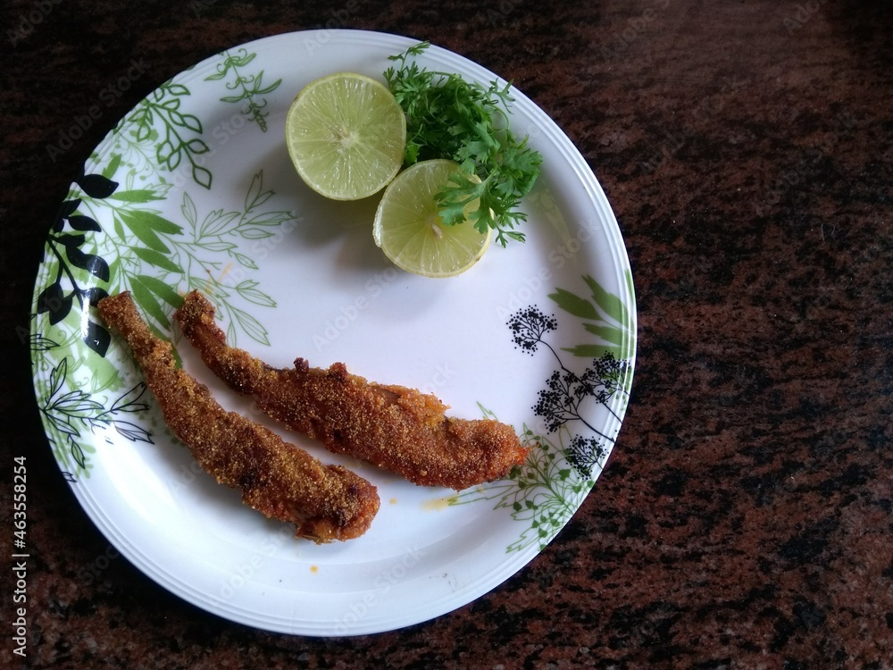 Fried Bombay duck fish or bombil in a plate with Lemon and coriander ...