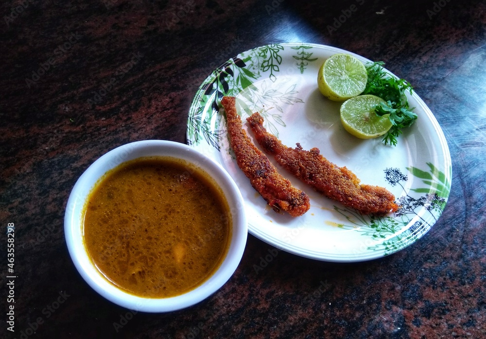 Fried Bombay duck fish or bombil in a plate with Lemon and coriander ...