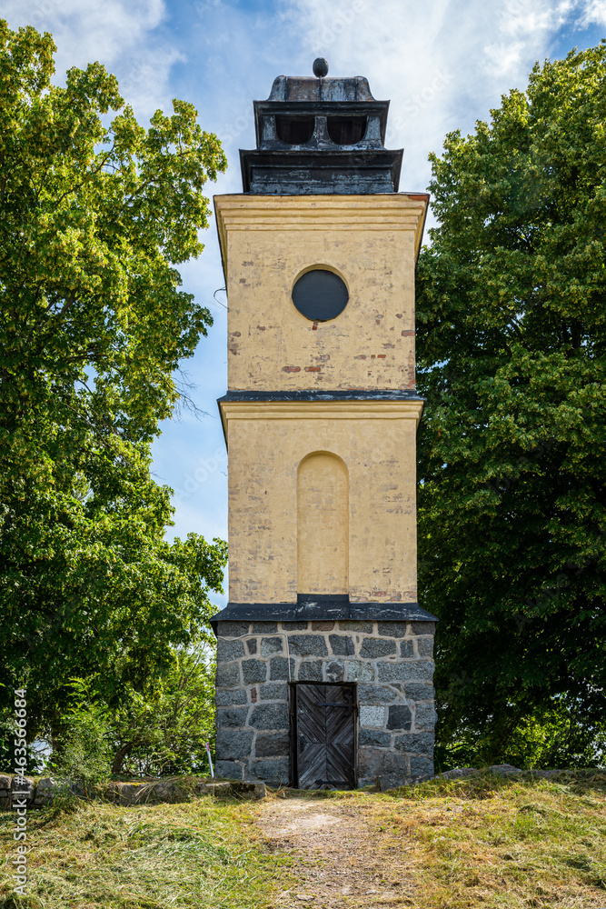 Beautiful old ancient yellow stone bell tower. Summer nature with green ...