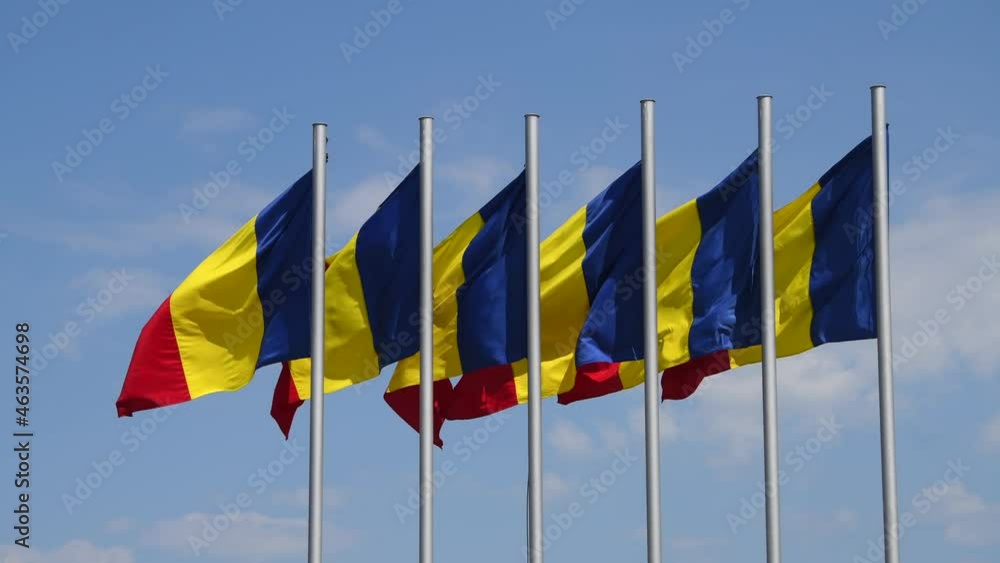 4K video with a lot of national flags of Romania winding on a blue sky ...