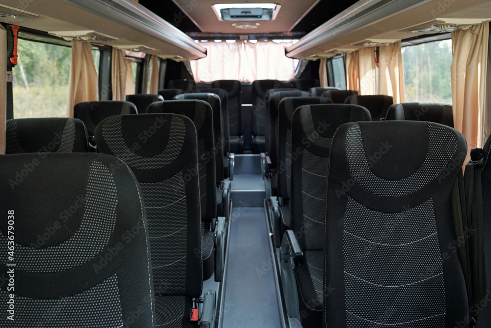 Two rows of grey and balck double seats and long aisle between them ...