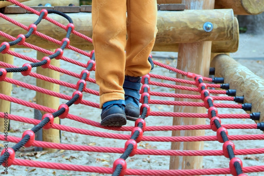 Child playing in the playground. Child's feet on a rope ride in autumn ...