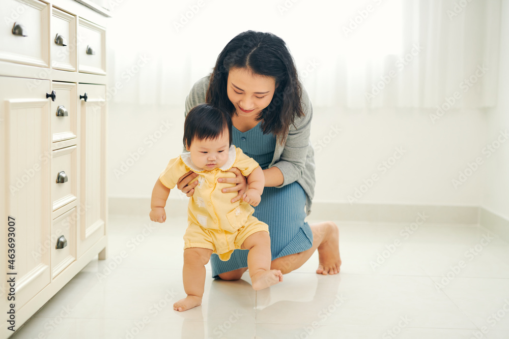 Mom teaching her girl's first baby steps at home Stock Photo | Adobe Stock