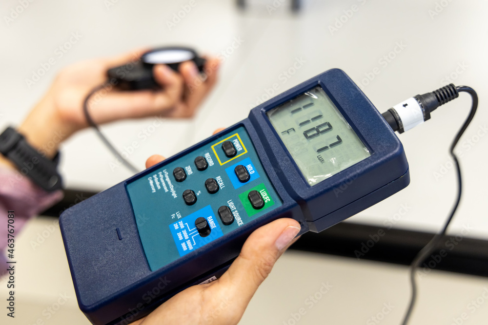 Hand holding Digital handheld light lux meter intensity of light with ...