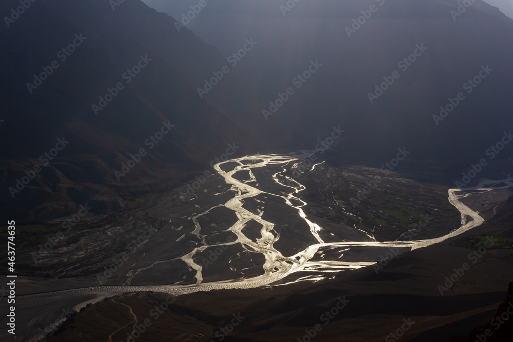 An aerial view of sun light hitting the Spiti river winding through the ...