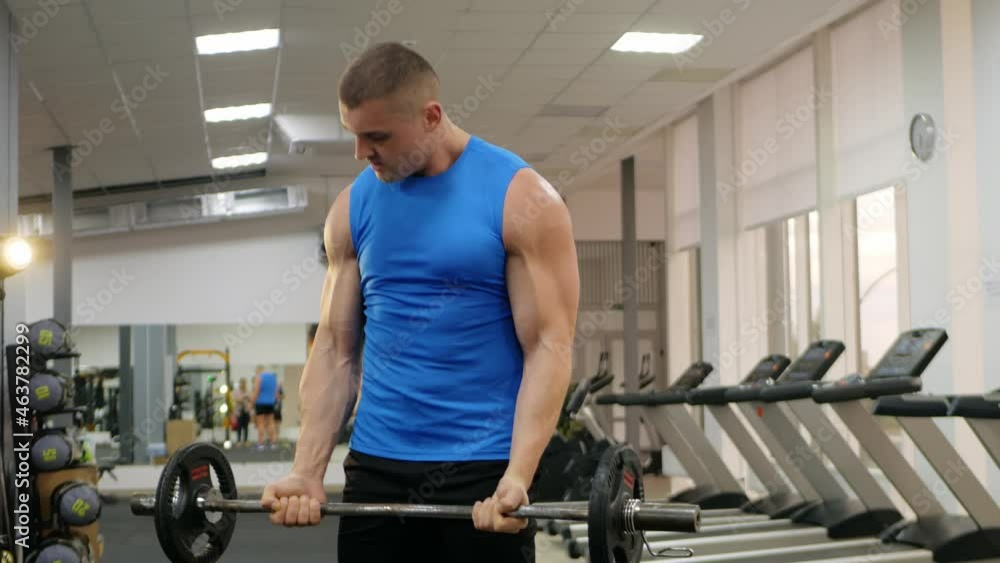 A young handsome coach with a muscular body poses in the gym ...