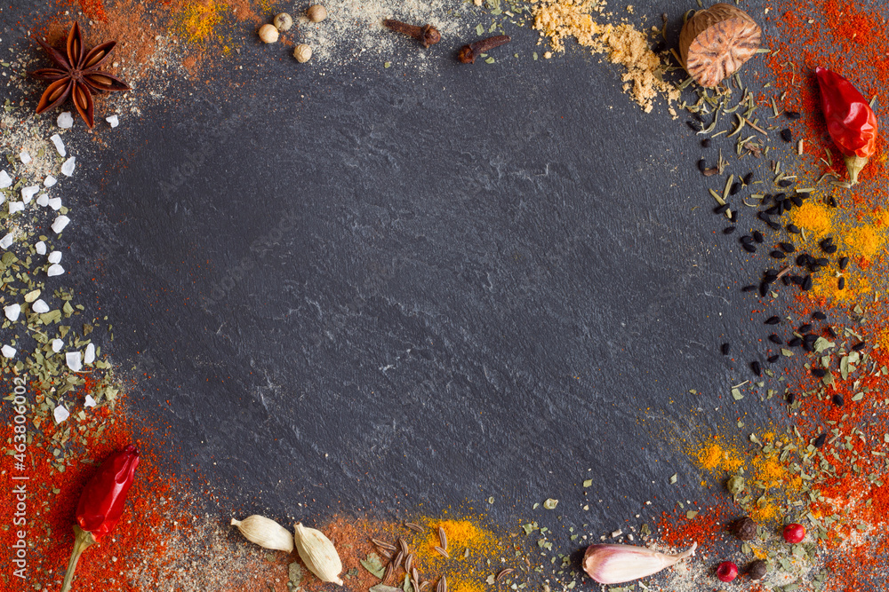 Variety aromatic spices in powder scattered on black stone background ...