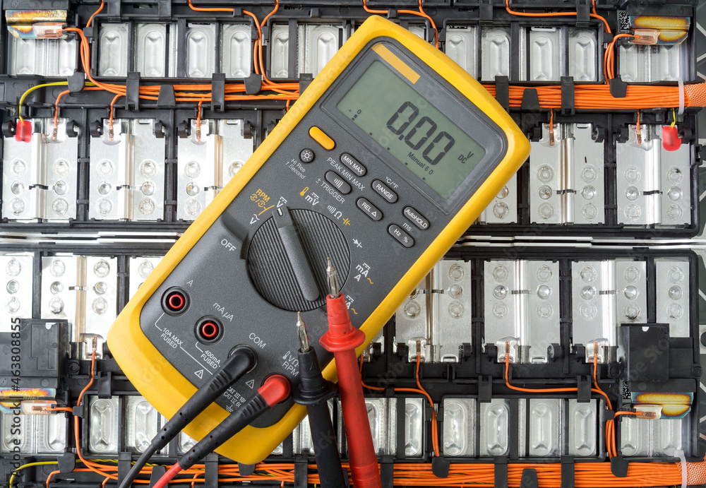 Yellow Digital multimeter with probes on Lithium ion battery background ...
