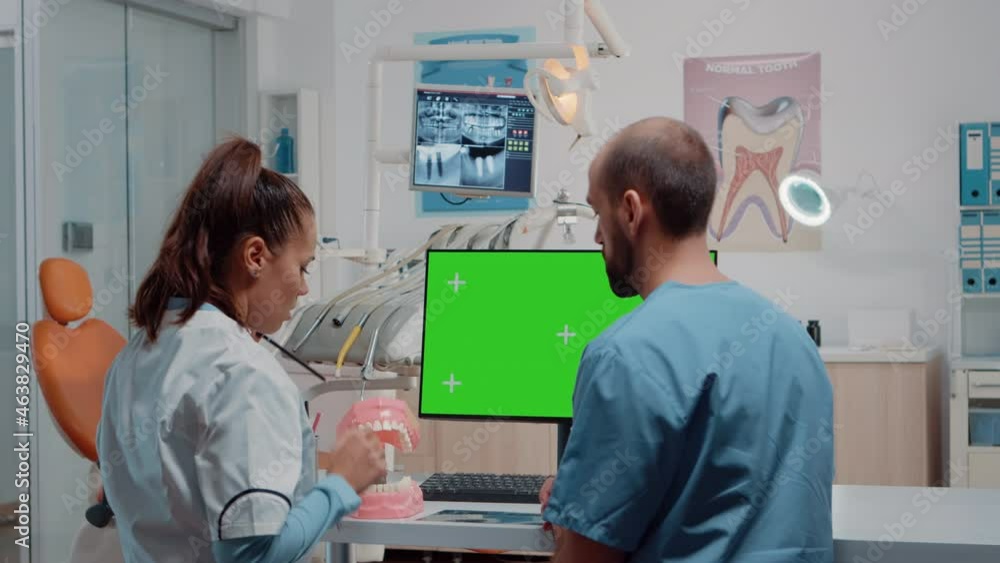 Woman dentist and man working with green screen on monitor while ...