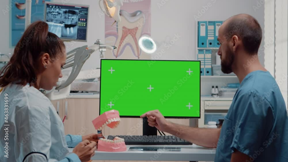 Oral care team looking at horizontal green screen on monitor while ...