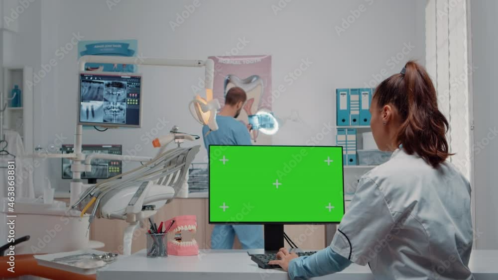 Dentist using green screen on monitor and talking to man assistant in ...