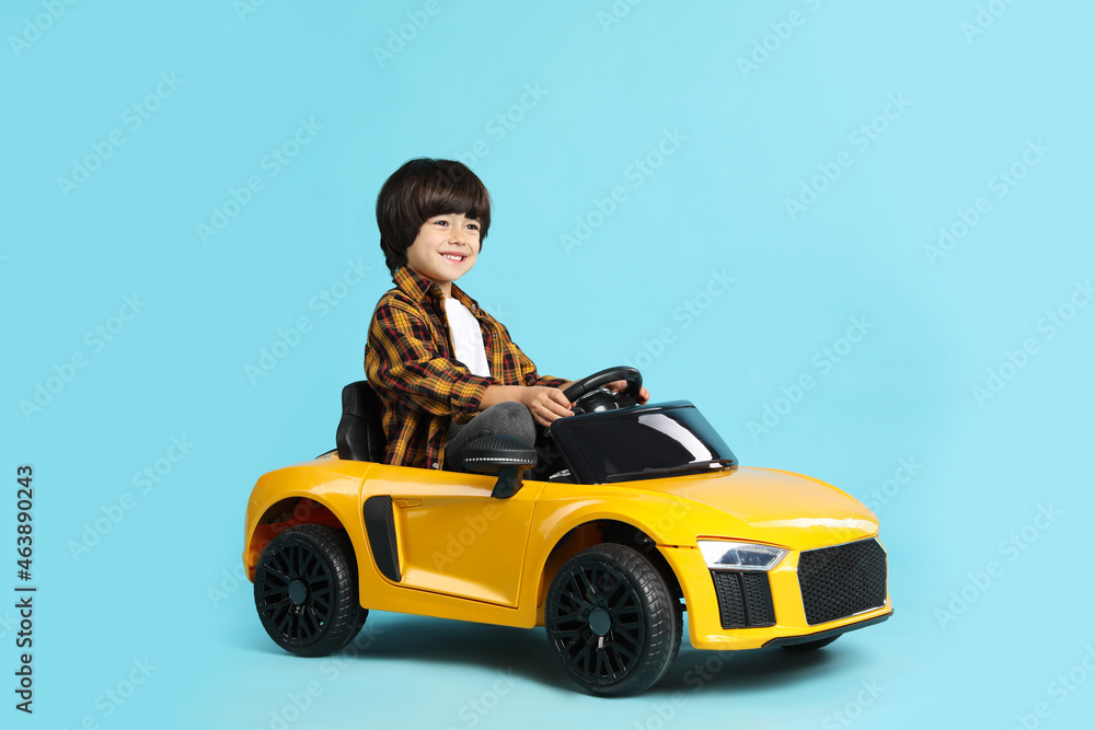 Little child driving yellow toy car on light blue background Stock ...