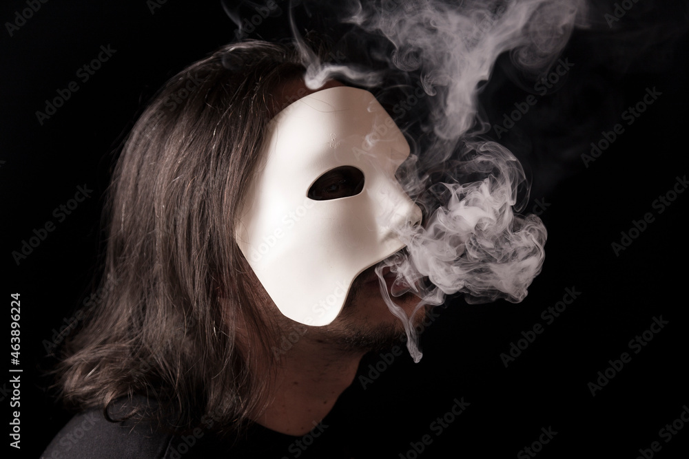 Portrait of a man wearing white mask with smoke coming out of his mouth ...