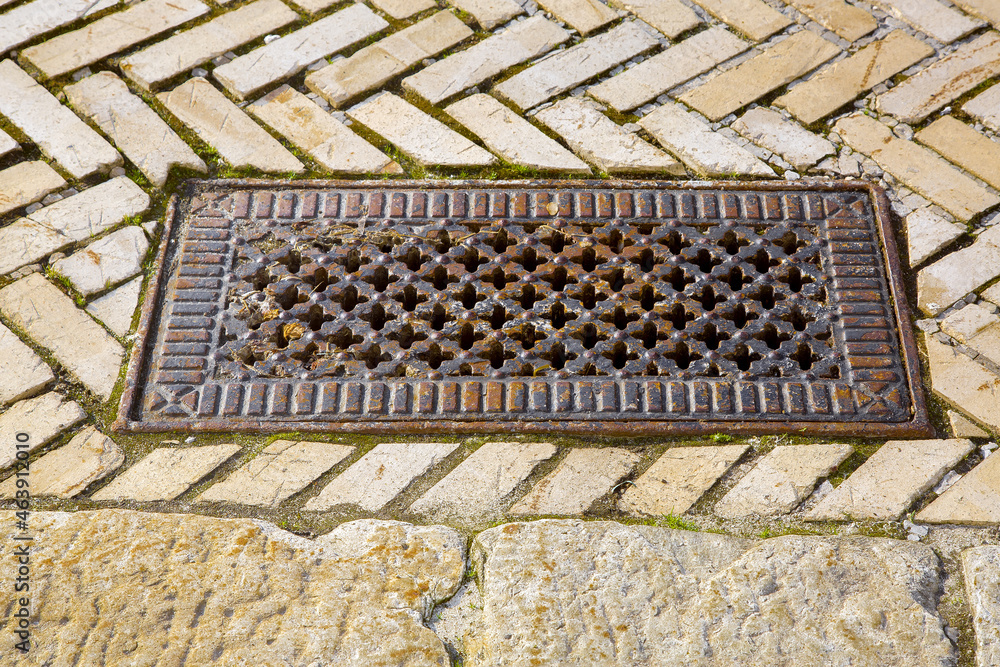 iron rusty rectangular manhole with shaped holes in form of crosses in ...