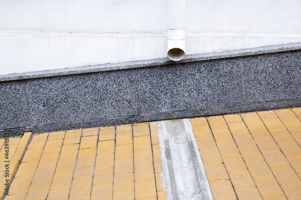 gray granite cladding on facade of a house wall with a drainage pipe ...