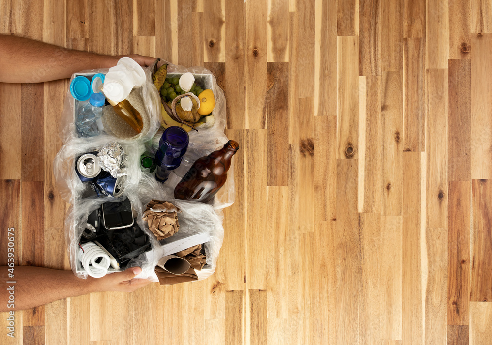 Hands holding different types of segregated waste materials on wooden ...