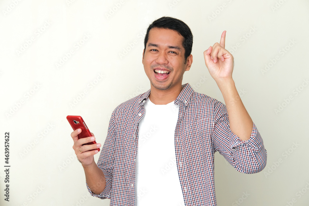 Adult man showing happy expression with finger pointing up when holding ...