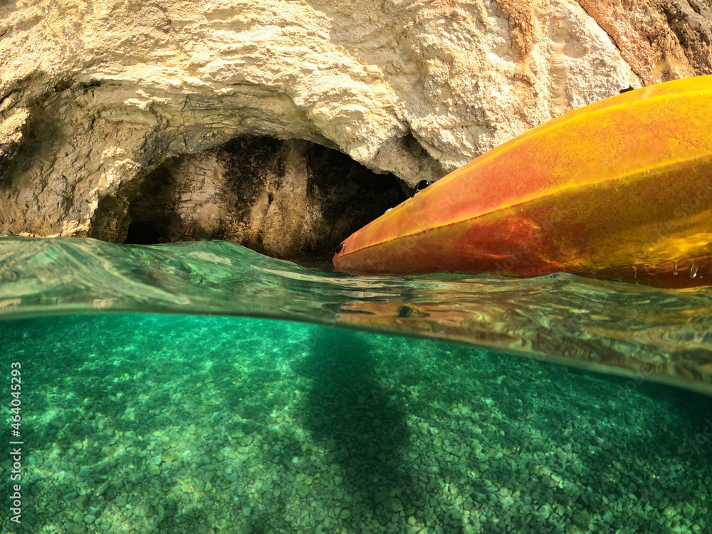 Underwater split photo of canoe in tropical exotic bay with sea caves ...