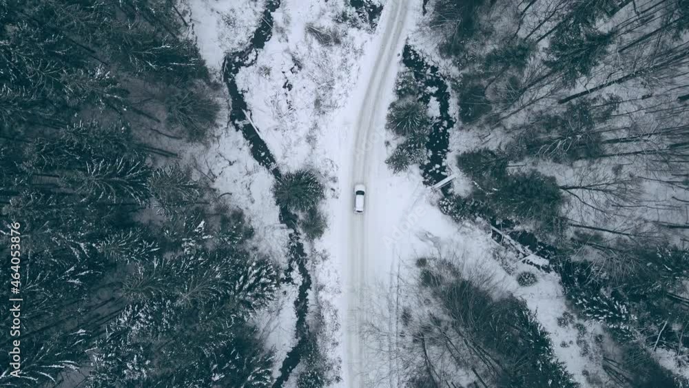 overhead top view car moving by snowed trail road by mountains forest ...