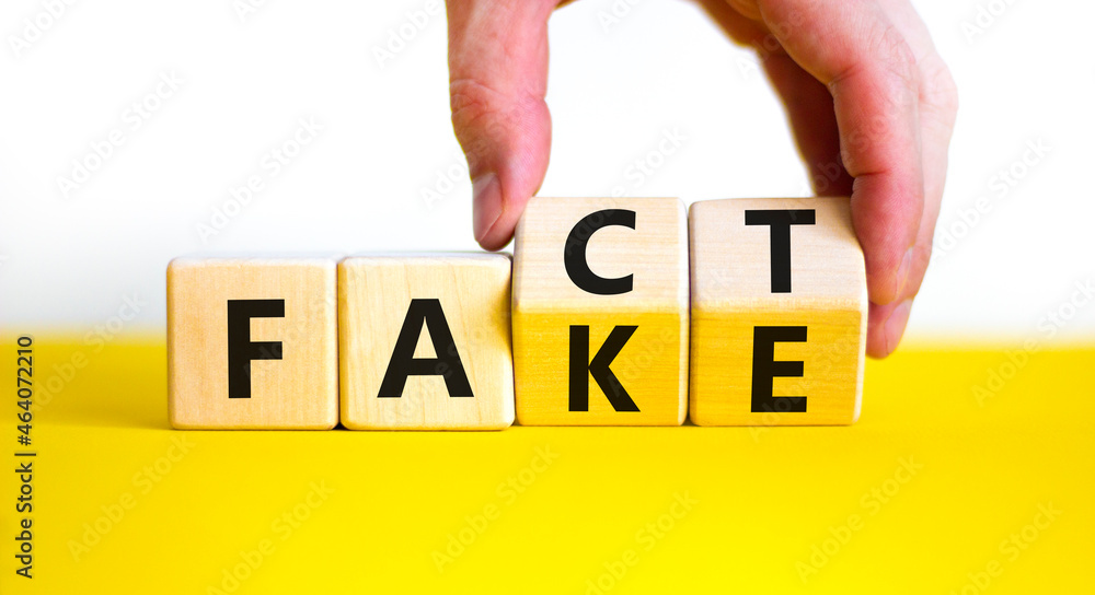 Fact or fake symbol. Businessman turn wooden cubes and changes the word ...