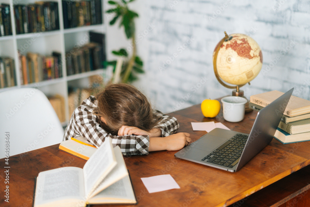 Side view of tired little child school girl sleeping at work desk lying ...
