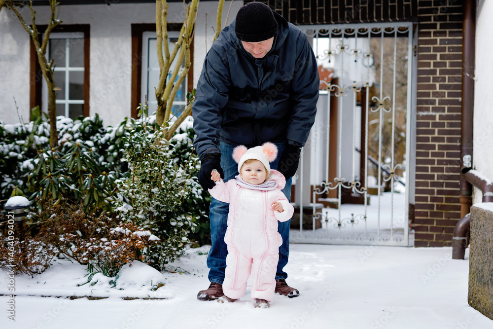 Adorable little baby girl making first steps outdoors in winter through ...