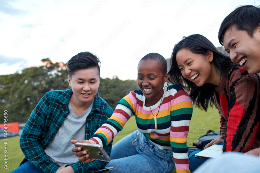 Group of young university students hanging out sitting on grass ...