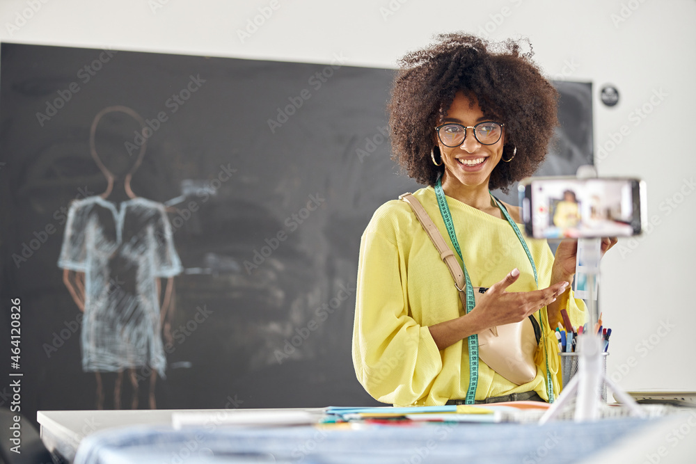 African-American tutor of clothes design course shows color palette to ...