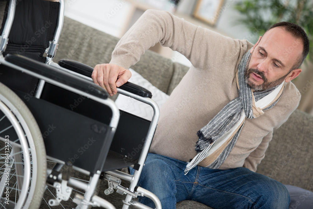 disabled man moving himself into a wheelchair Stock Photo | Adobe Stock