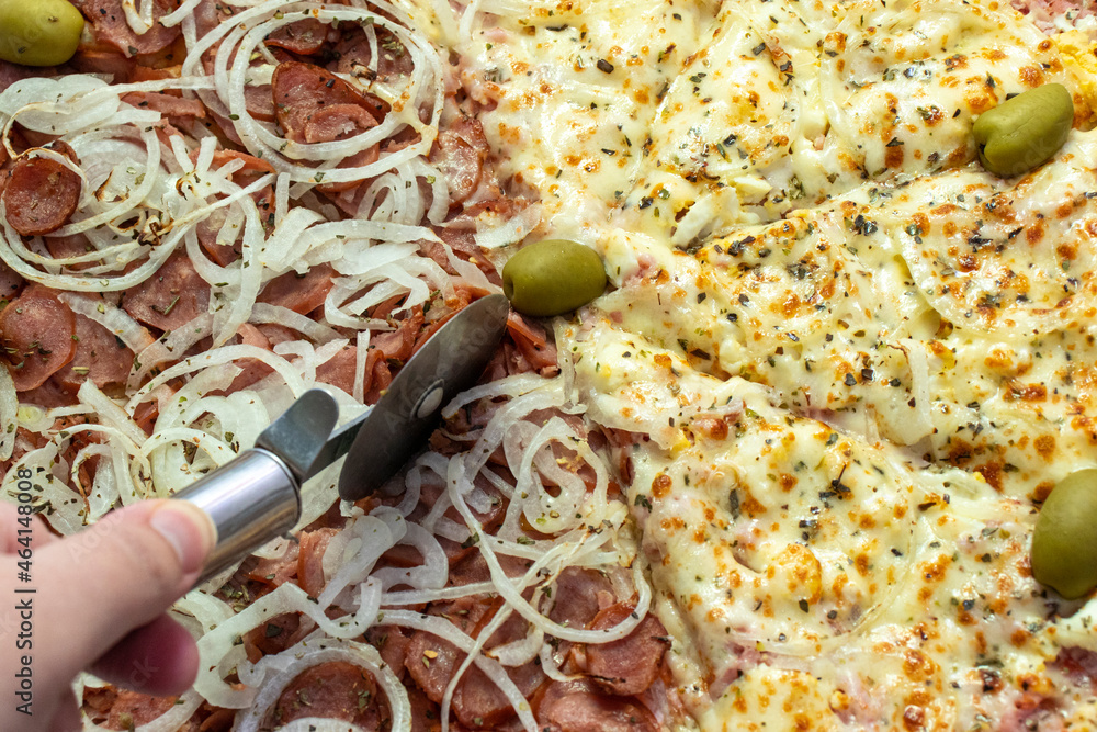 Cortando uma pizza metade calabresa e metade portuguesa. Stock Photo ...